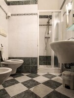 Casa de banho com sanita, bidé e cabine de duche.