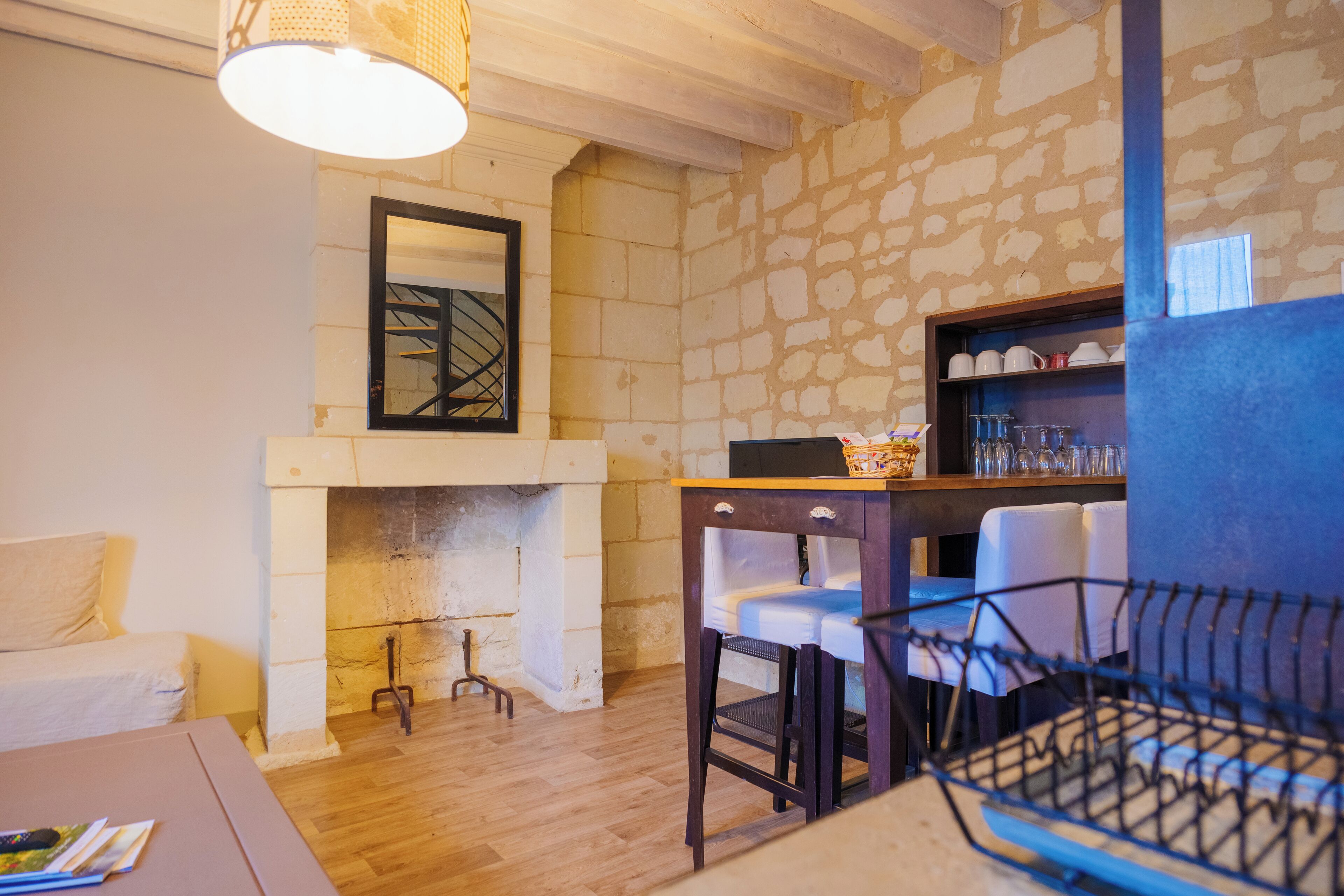Um quarto acolhedor com parede de pedra, lareira, mesa de madeira e um bar com banquetas e adega.