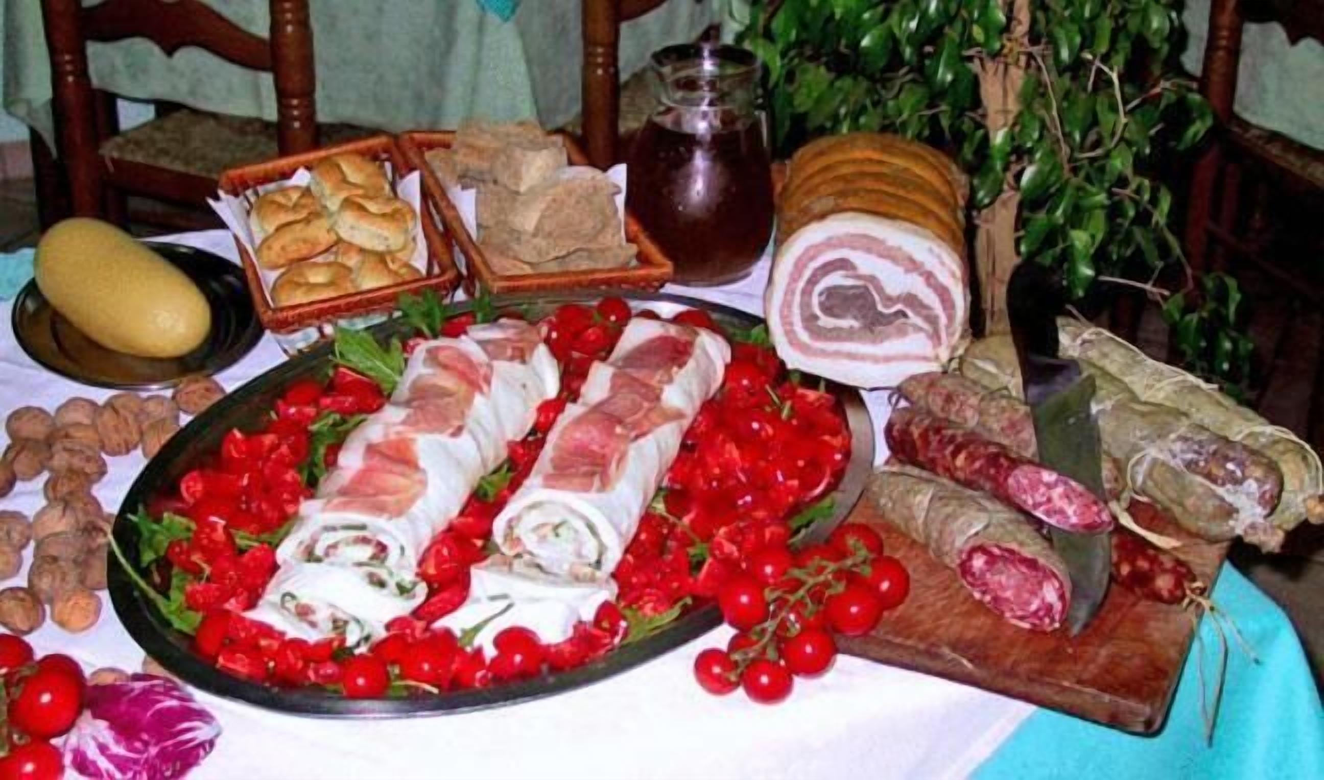 Diversos alimentos, incluindo charcutaria, pão e uma saladeira de frutas.