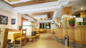 Restaurante com mobiliário de madeira, balcão e televisão.
