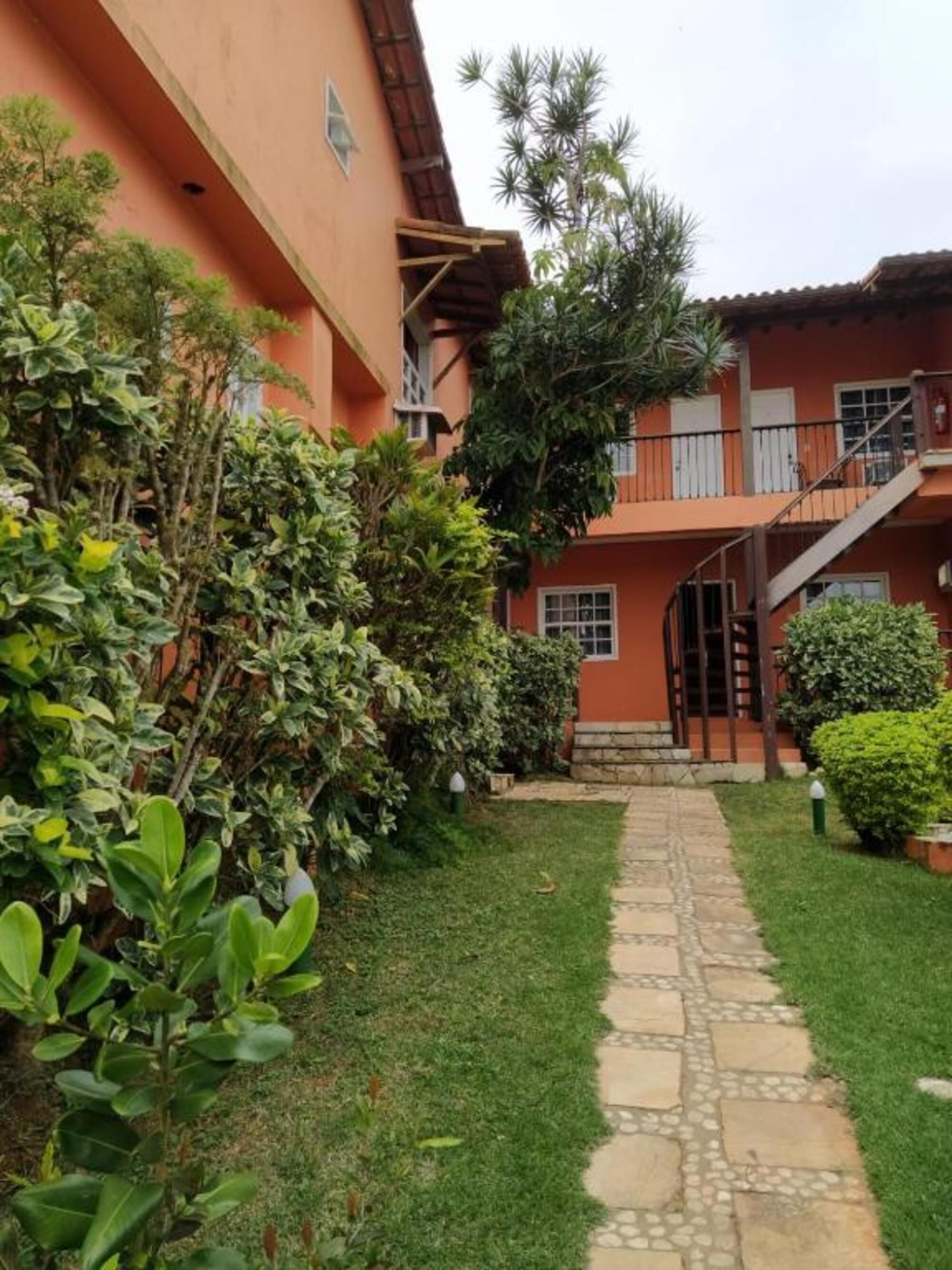 Um edifício com um caminho de pedra que leva a um portão, cercado por vegetação exuberante e diversas plantas.