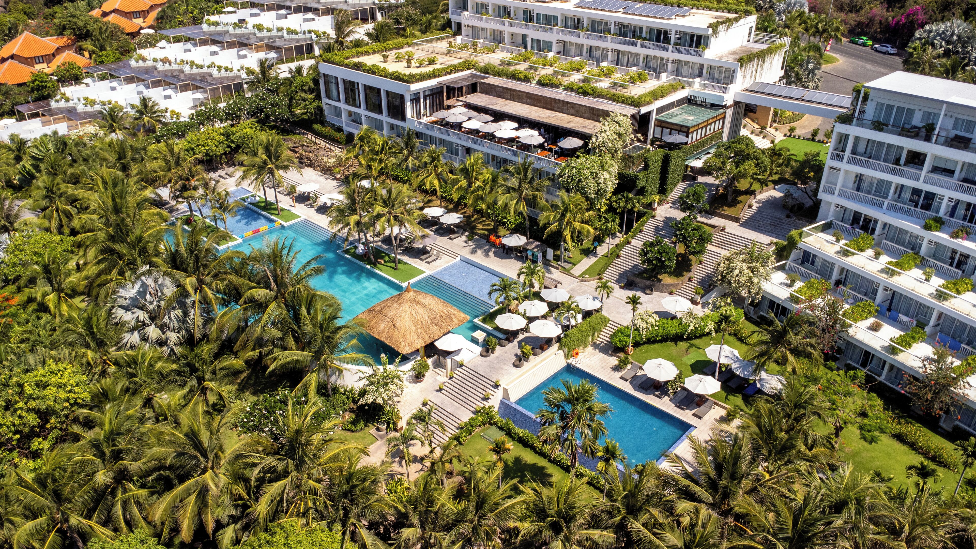 Um resort com várias piscinas, palmeiras e edifícios modernos.