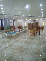 Um hall amplo com um elemento central de água, áreas de estar e piso estampado.
