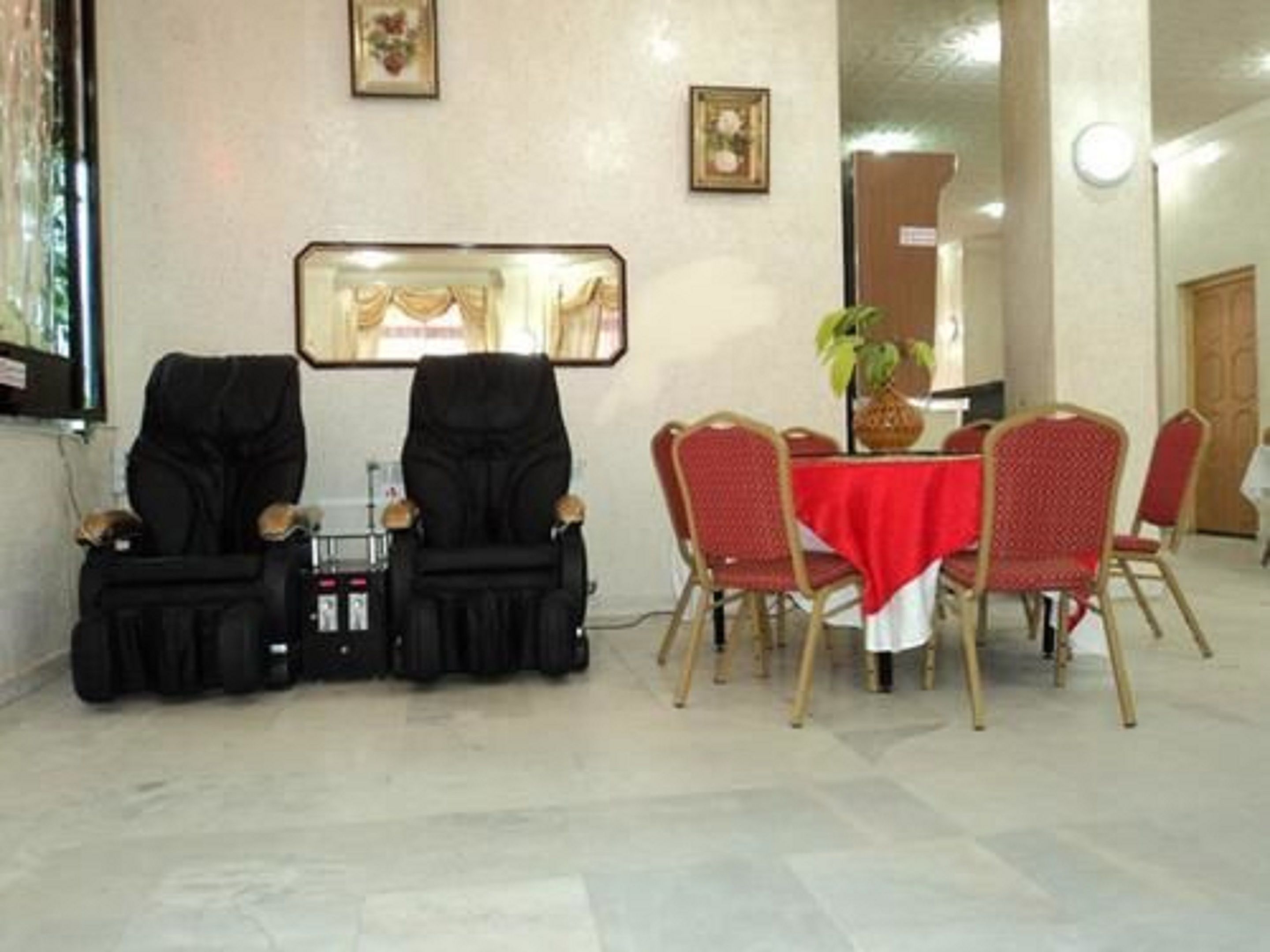 Uma sala de jantar com toalha de mesa vermelha, cadeiras vermelhas e uma cadeira preta. Há uma planta na mesa e um espelho na parede.
