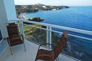 Varanda com cadeiras de vime com vista para a costa.