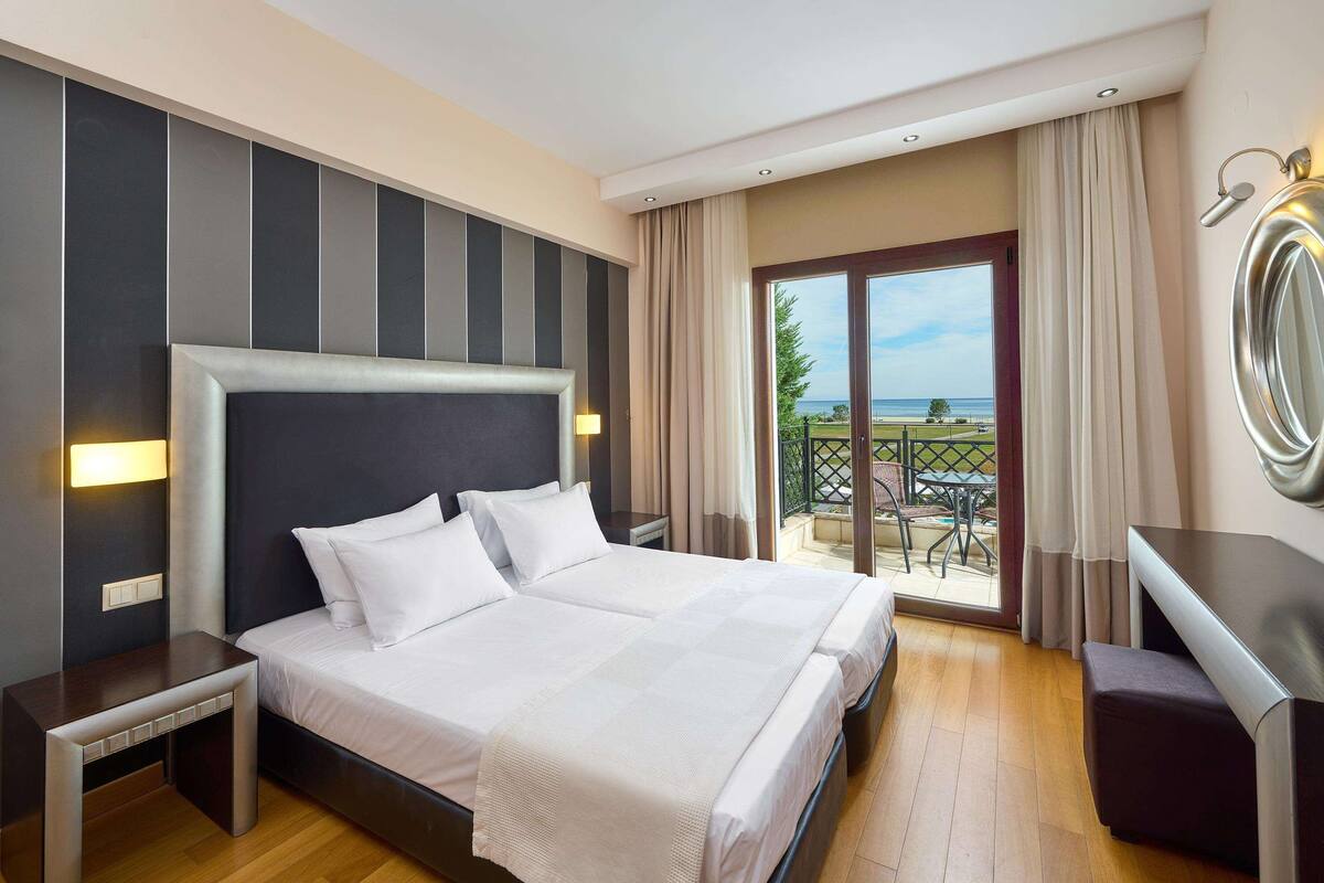 Quarto de hotel com uma cama grande, uma escrivaninha e vista para o exterior.