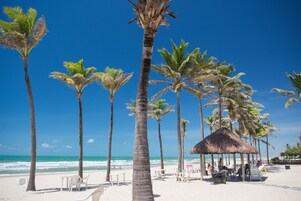 Na praia, espreguiçadeiras, toalhas de praia, voleibol de praia 