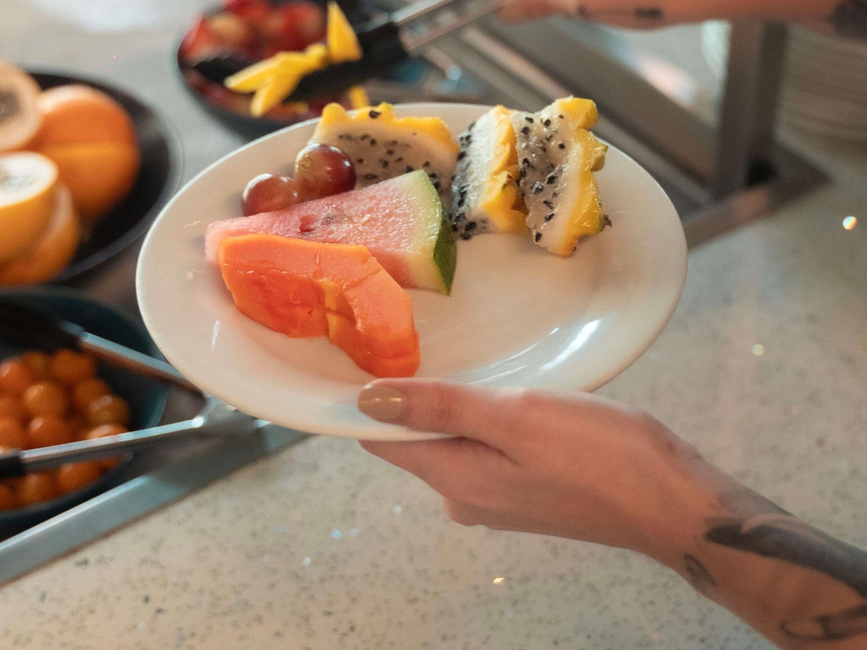 Uma pessoa segurando um prato com várias frutas.