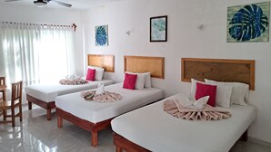 Quarto de hotel com duas camas de solteiro, cabeceiras de madeira, roupa de cama branca e um ventilador de teto.