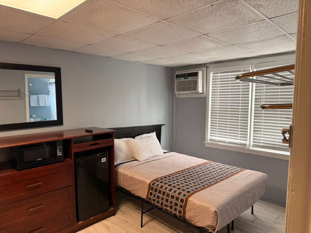 Quarto com cama, penteadeira, micro-ondas e ar condicionado.