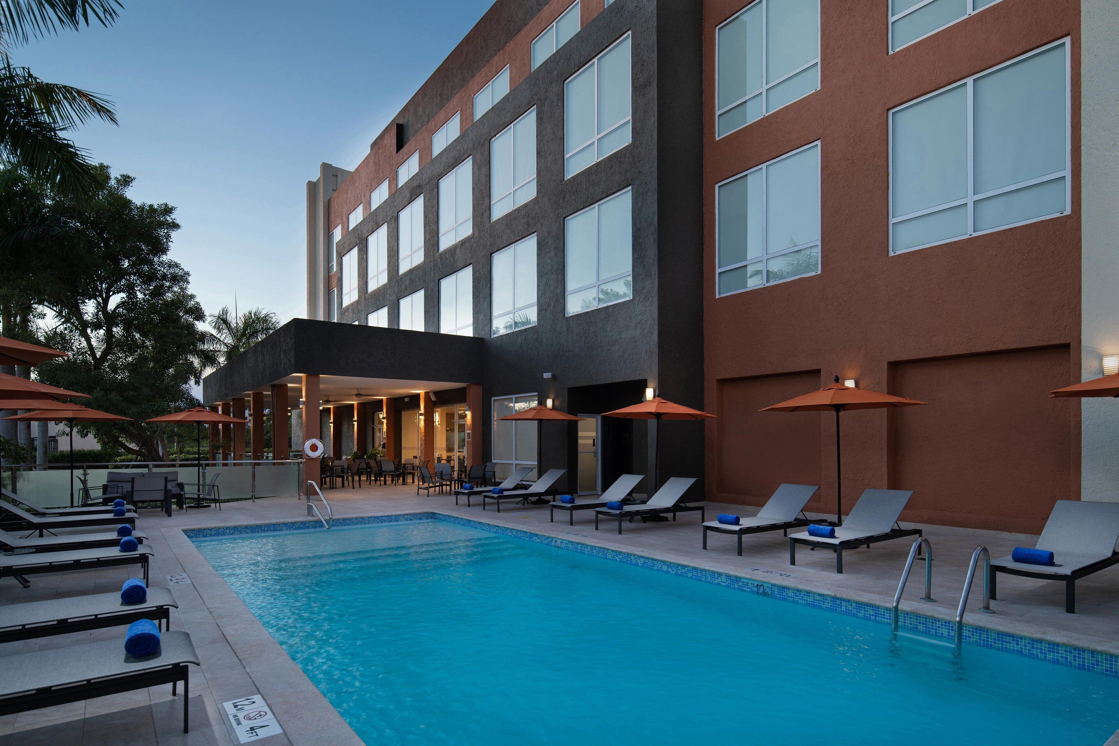 Um hotel com piscina, espreguiçadeiras e guarda-sóis.