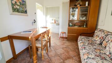 Um espaço compacto com área de refeições, sofá e cozinha ao fundo.