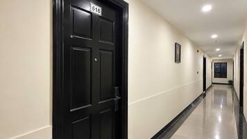 Corredor com porta preta identificada com o número 616, dando acesso a um quarto.
