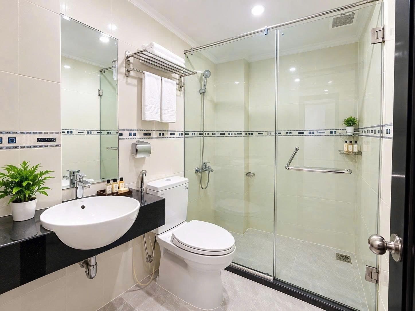 Casa de banho moderna com chuveiro envolto em vidro, lavatório branco e sanita.