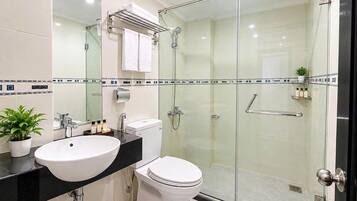 Casa de banho moderna com chuveiro envolto em vidro, lavatório branco e sanita.