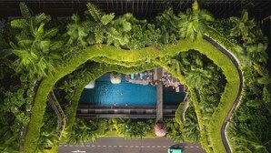 Vista aérea de um estacionamento com piscina, rodeado por vegetação exuberante e palmeiras.