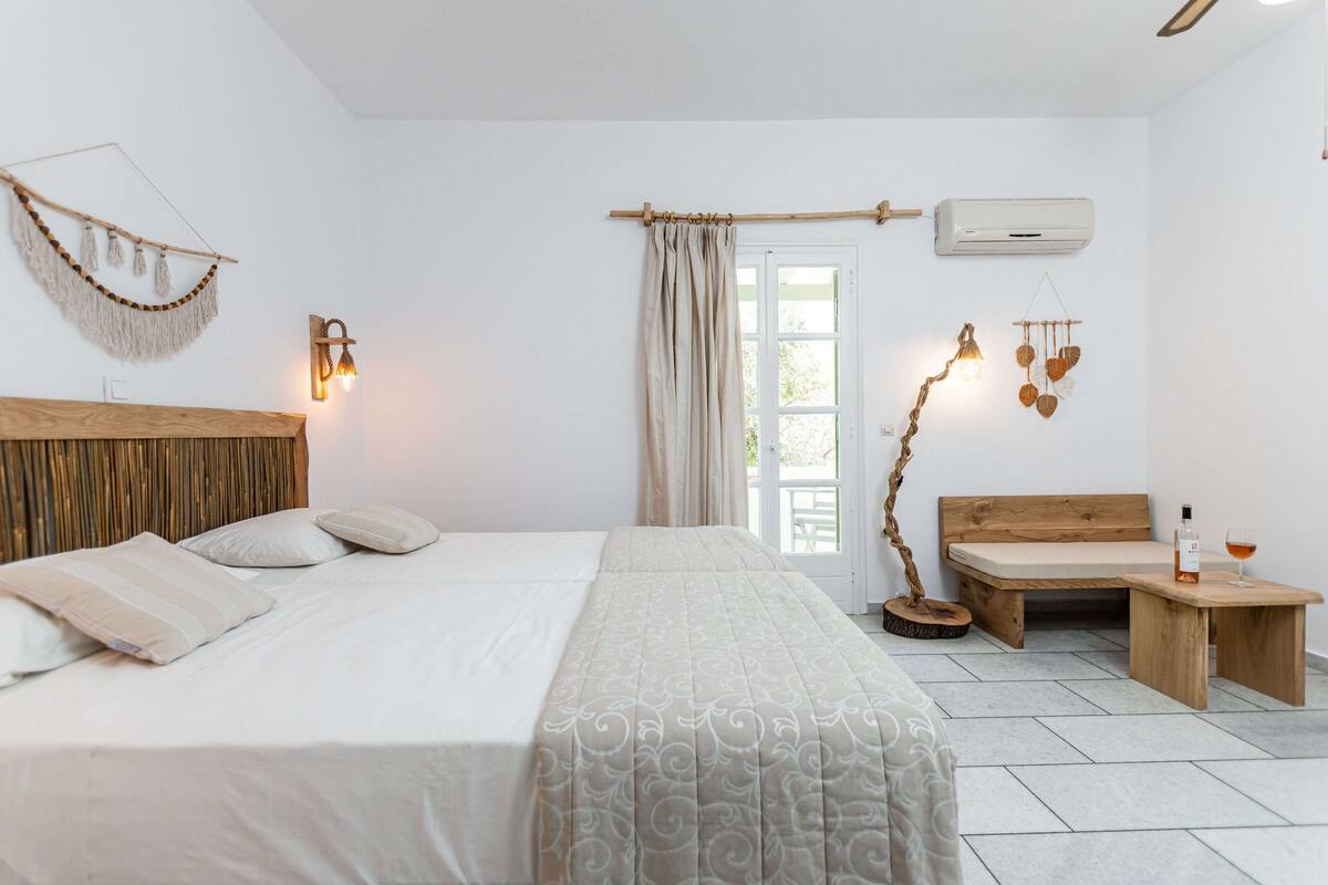 Quarto com cama, mesa de cabeceira e um banco.