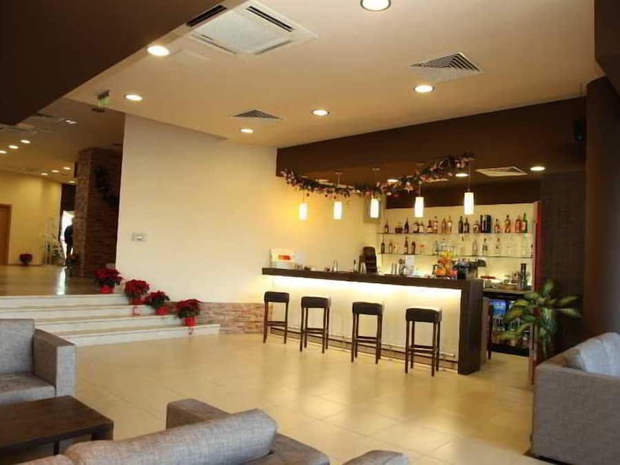 Um saguão de hotel com área de bar, assentos e escada que leva a outro andar.