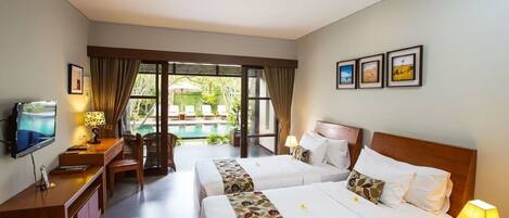 Quarto de hotel com duas camas, uma escrivaninha, televisão e vista para a piscina.