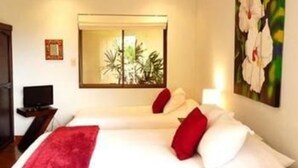 Quarto de hotel com cama, televisão e pintura de flores.