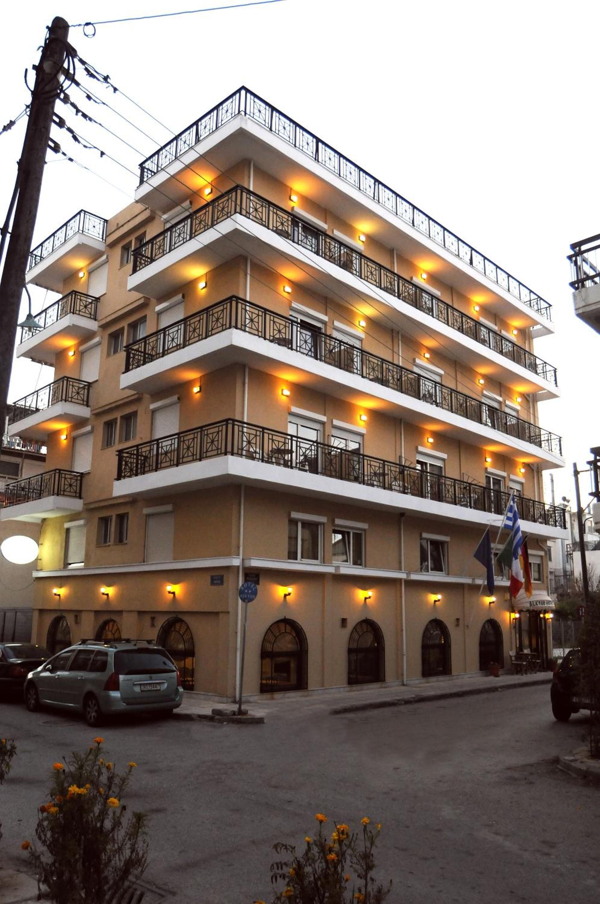 Hotel de vários andares com varandas, entrada no nível da rua e uma bandeira.