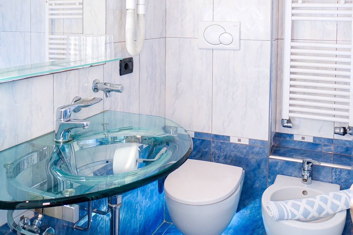 Uma casa de banho moderna com lavatório de vidro, sanita e bidé.