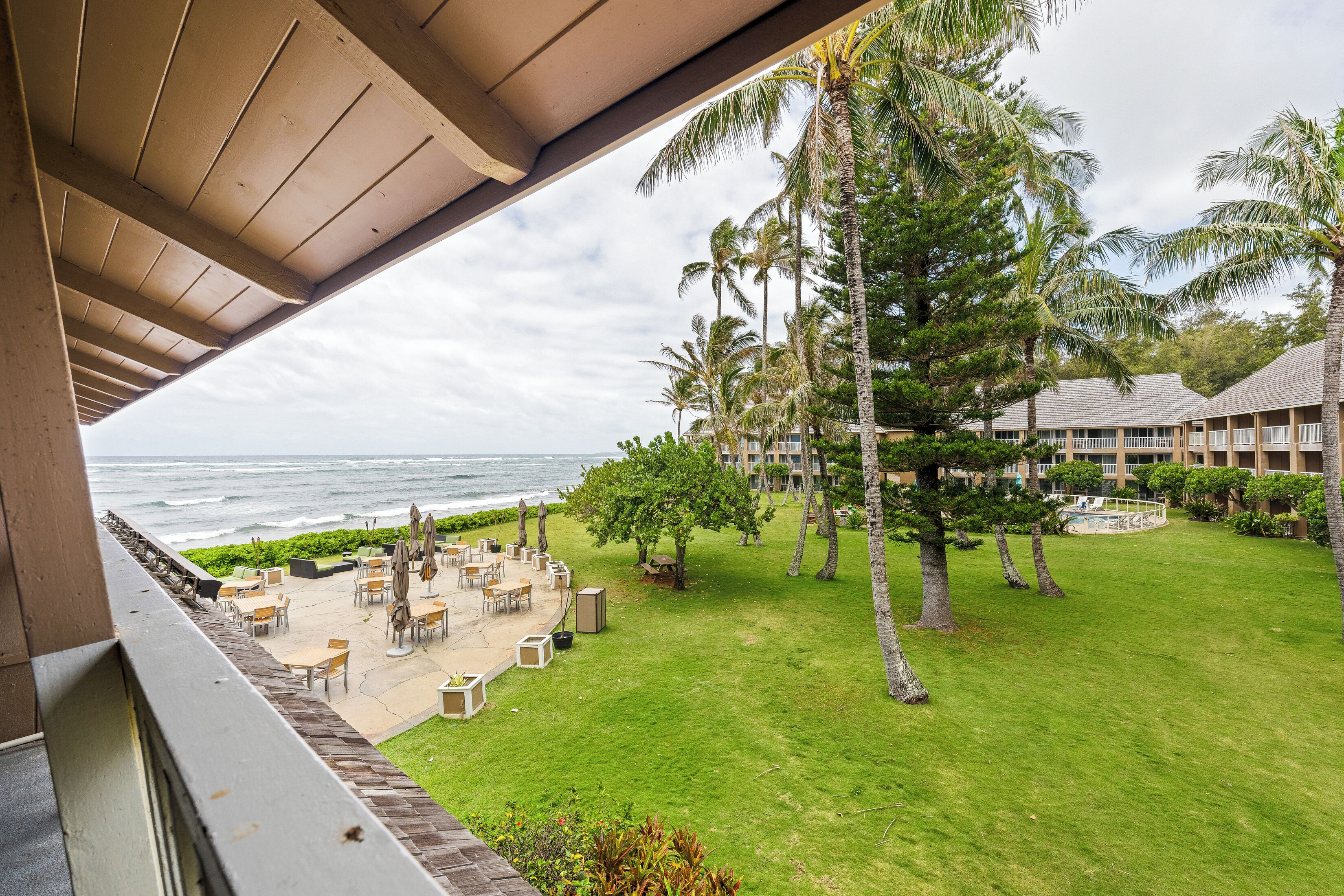 Hotel com vista para o oceano, área de estar externa e palmeiras.