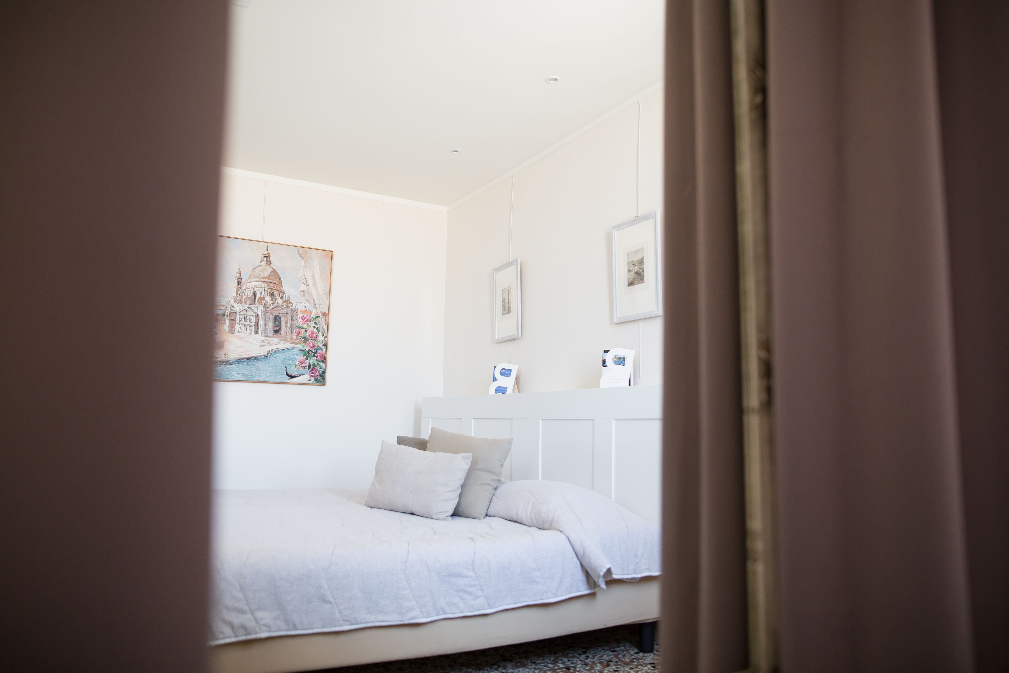 Um quarto com uma cama, um quadro e fotografias emolduradas na parede.