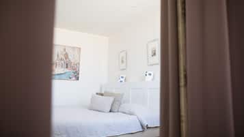 Um quarto com uma cama, um quadro e fotografias emolduradas na parede.