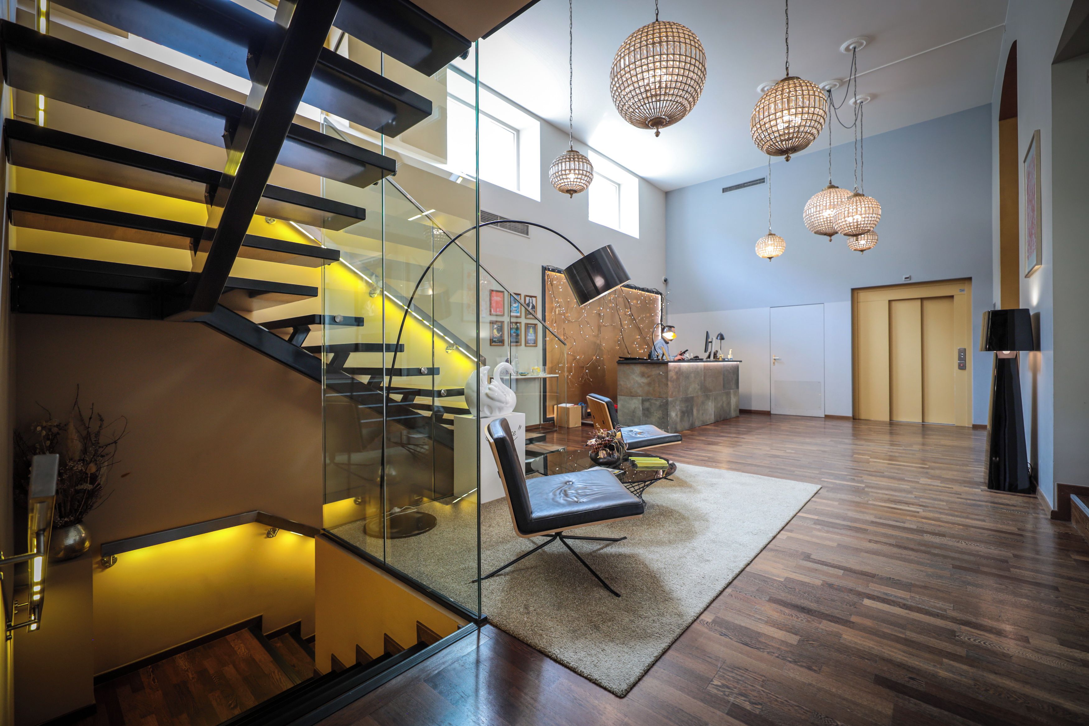 Interior moderno com escada, área de estar e luminárias pendentes.