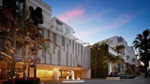 Um hotel moderno com um sinal chamativo 'aka', um pátio central com uma escultura e um jardim bem cuidado.