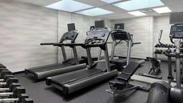 Uma academia com esteiras, halteres e aparelhos de musculação.