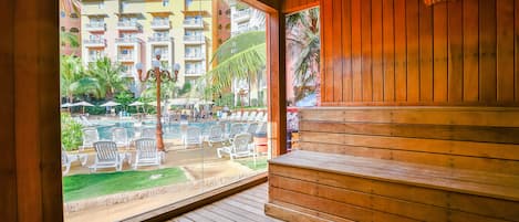 Um deck de madeira com vista para uma área de piscina e um edifício com varandas.