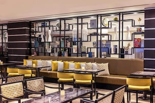 Uma área de lounge moderna com sofá, cadeiras amarelas e mesas.