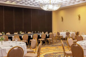 Uma sala de conferência com mesas redondas, cadeiras e um candelabro.