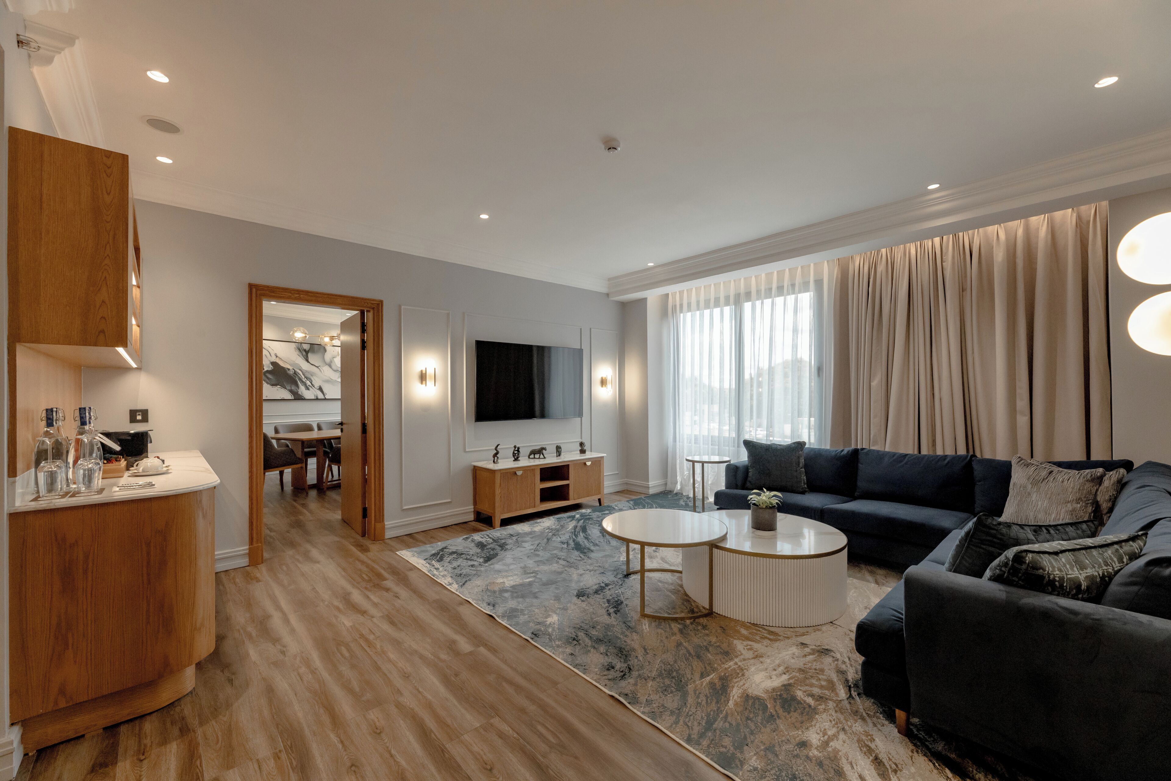Uma sala de estar moderna com sofá, mesa de centro, televisão e aparador de madeira.