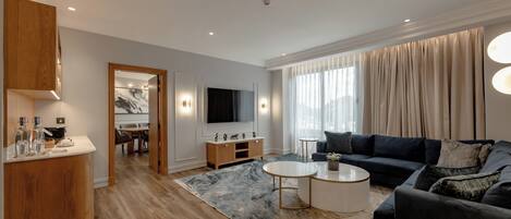 Uma sala de estar moderna com sofá, mesa de centro, televisão e aparador de madeira.
