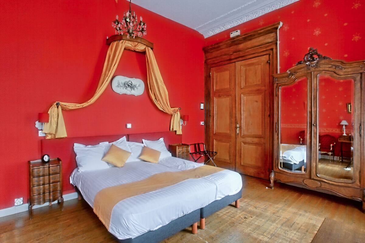 Quarto com uma cama grande, um guarda-roupa de madeira e um espelho.