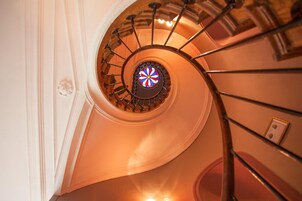 Uma escadaria em espiral com uma janela de vitrais no topo.