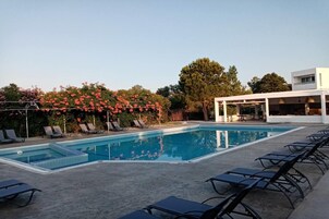 Piscina com espreguiçadeiras e área de estar coberta.