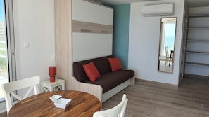 Quarto moderno com sofá, uma mesinha e uma cadeira.