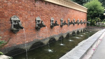 Paredes de tijolos com vários bicos de água em forma de pássaros e um estreito canal de água.