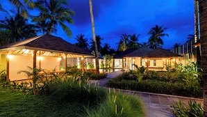 Um resort com várias villas para hóspedes, um caminho pavimentado e vegetação tropical exuberante.