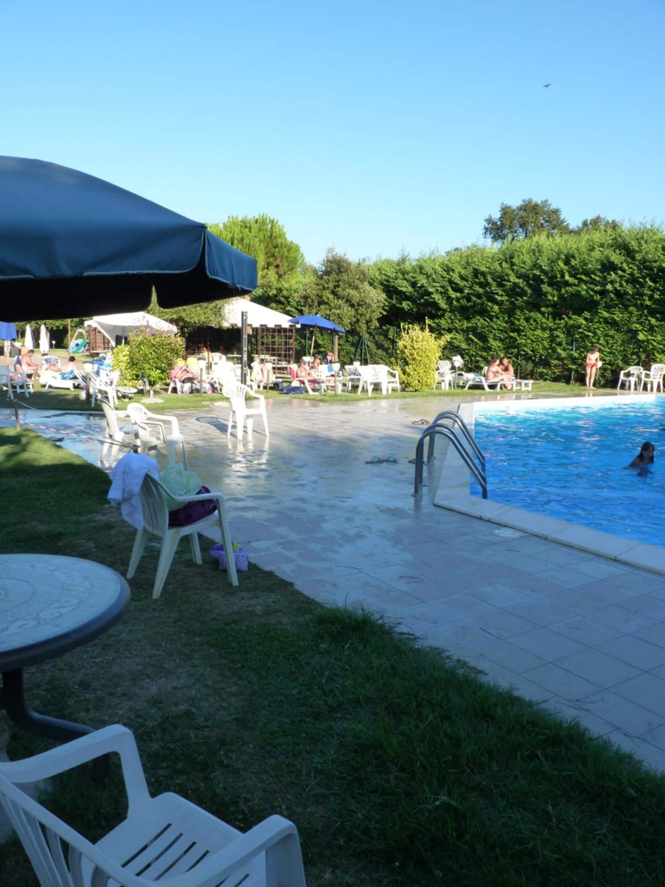 Uma área na piscina com espreguiçadeiras e guarda-sóis, céu claro e piscina.