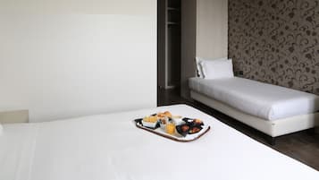 Quarto de hotel com uma cama, um pequeno sofá e uma bandeja com itens de café da manhã.