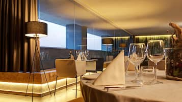 Uma área de jantar moderna com uma mesa posta para dois, uma luminária e taças de vinho.