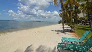 Praia particular, areia branca, espreguiçadeiras, guarda-sóis