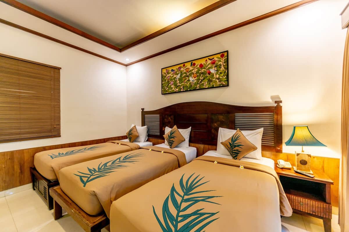 Quarto de hotel com duas camas, cabeceiras de madeira, mesa de cabeceira com abajur e um quadro na parede.