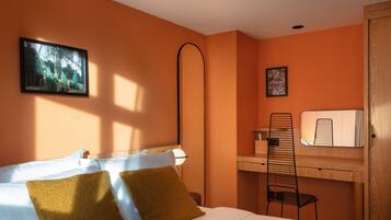 Quarto de hotel com uma cama, escrivaninha e uma cadeira.