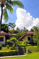 Um resort tropical com uma escadaria que leva a um edifício, rodeado por vegetação exuberante e palmeiras.